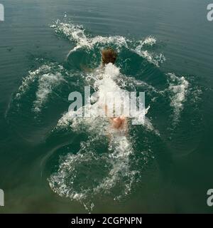 Water splashes after man jumping and diving into the swimming pool ...
