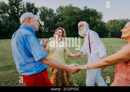 Group of youthful seniors having fun outdoors - Four pensioners bonding ...
