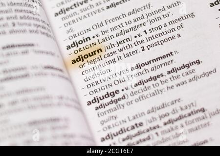 The word or phrase Adjourn in a dictionary highlighted with marker ...