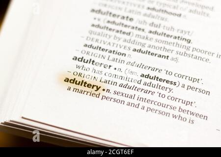 The word or phrase Adultery in a dictionary highlighted with marker ...