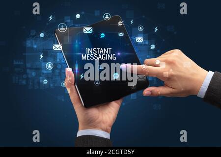 Businessman holding a foldable smartphone with INSTANT MESSAGING ...