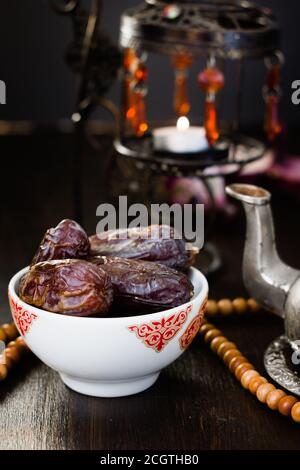 Dates in wooden bowl and lantern on stone table. Muslim holy month ...