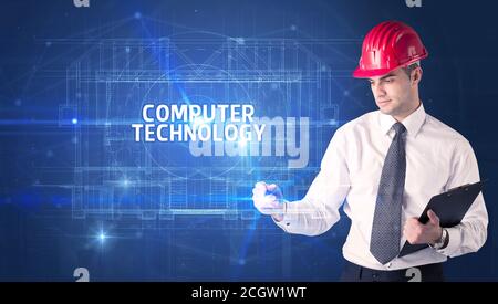 Handsome architect with helmet drawing COMPUTER TECHNOLOGY inscription ...