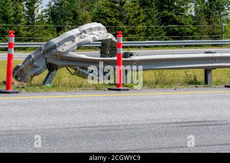 A bent and twisted guard rail at the side of a highway.It appears to ...