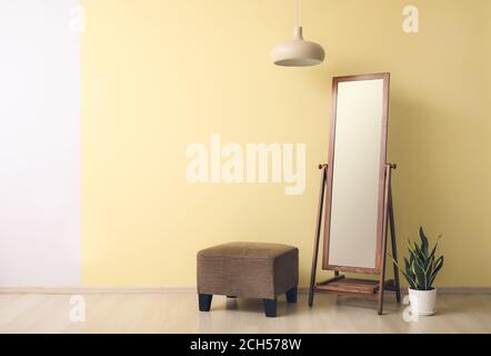 Big mirror and pouf near color wall in room Stock Photo - Alamy