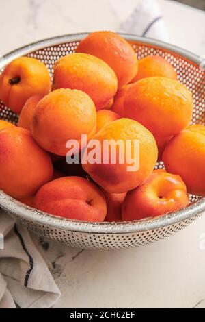 Colander with tasty ripe apricots on light background, top view Stock ...