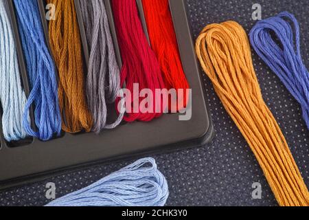 Colorful cross stitch embroidery threads on a black background. Close ...