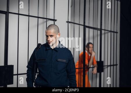 A prison warden guards cells with prisoners sentenced to life in orange ...