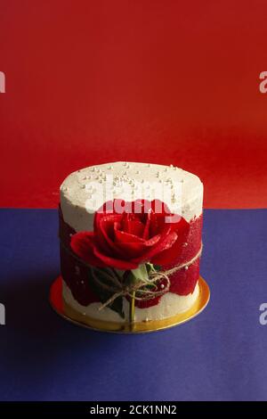 Vertical shot of a small fancy cake with a red rose on a white tray ...