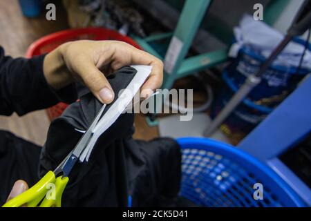 Female worker hand cutting lining paper on staff uniform on Garment ...