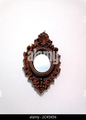 Vertical shot of a vintage mirror with decorative border against a ...