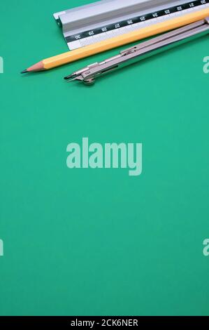 Vertical shot of technical drawing tools on a green background with a ...