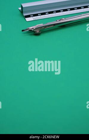 Vertical shot of technical drawing tools on a green background with a ...
