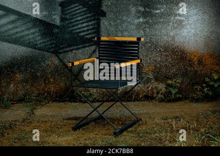 Closeup of a director's black chair, chair shadow on the back wall ...