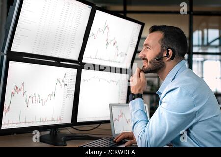 Stock Traiding. Trader wearing headset sitting at office in front of ...