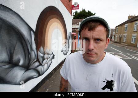 Street artist Nathan Murdoch poses with his art against racism mural in ...