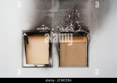 house or home fire - boarded up windows and burned facade blackened by ...