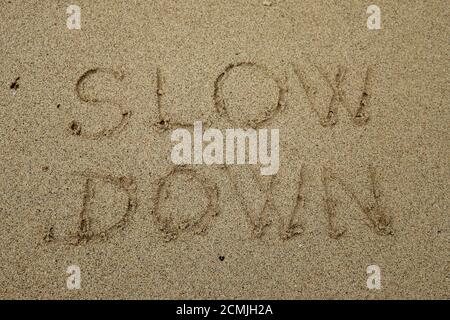 slow down, mindfulness concept written on sand Stock Photo - Alamy
