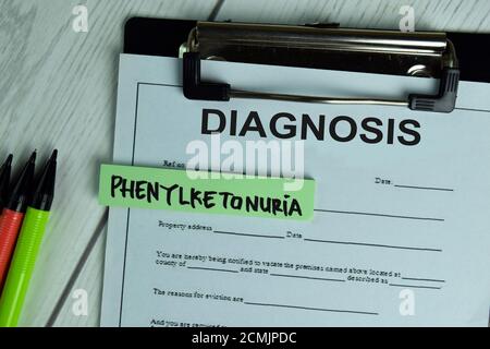 Phenylketonuria write on a book isolated on Wooden Table. Medical or ...