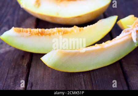 Pieces of ripe melon on a brown wooden table Stock Photo - Alamy