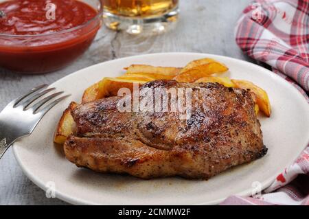 Juicy, browned pork steak on a bone with fried potatoes Stock Photo - Alamy