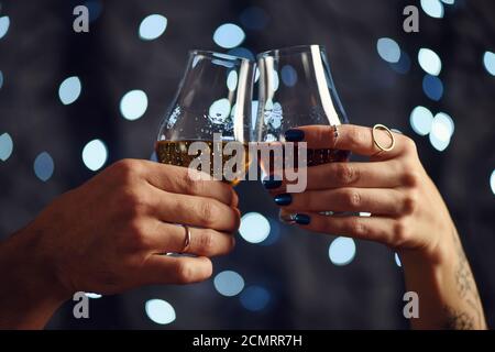 A couple makes a toast with two glasses of whiskey on wooden table, top ...