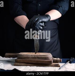 A wooden cutting board holds a knife, a piece of sliced salami, and a ...