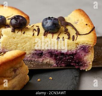 baked round cottage cheese casserole on a black plate, close up, tasty ...