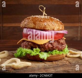 cheeseburger with tomatoes, onions, barbecue cutlet and sesame bun on ...
