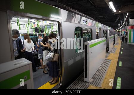 Commuters wearing face masks inside a train at the Hamamatsucho station ...