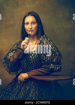 Smoking. Young woman as Mona Lisa, La Gioconda isolated on dark green ...