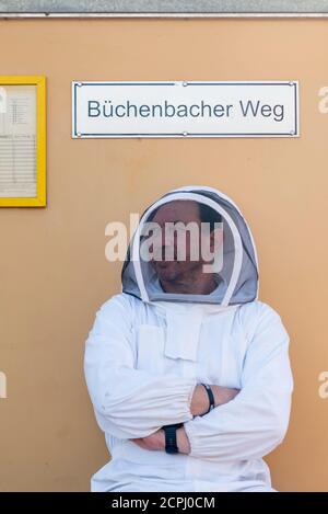 Side view of male beekeeper in protective costume harvesting honey from ...