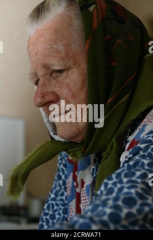 European grey-haired grandma wearing glasses and showing vertical photo ...