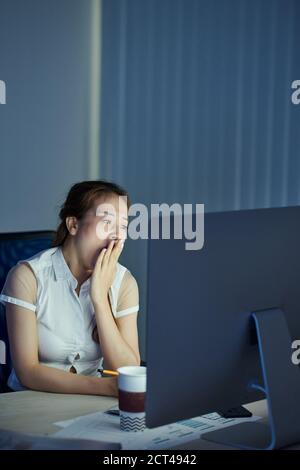 A tired and sleepy young Asian businesswoman or female office worker ...
