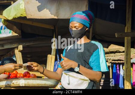 Afro-American female selling vegetables in a facial mask - concept of ...