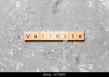 VALIDATE word written on wood block. VALIDATE text on cement table for ...
