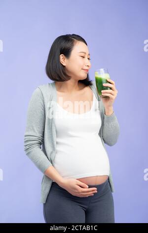 Pregnant woman with glass of green smoothie standing at home Stock ...