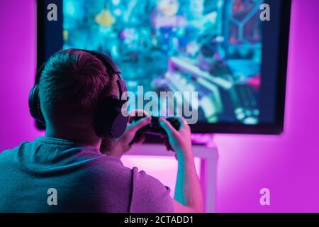 Back Shot of a Gamer Playing First-Person Shooter Online Video Game on ...