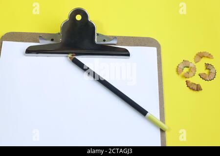 Shot of a drawing board with colored pencils on a yellow background ...