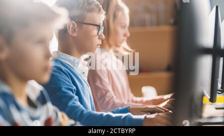 Young girl sitting in a coding classroom, using a laptop to practice ...