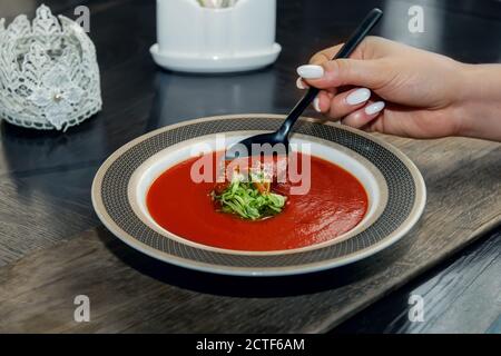 Smooth red gazpacho in rustic gray bowl with basil leaves on top. Fresh ...