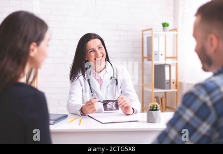 Female fertility doctor showing sonogram image after IVF to young ...