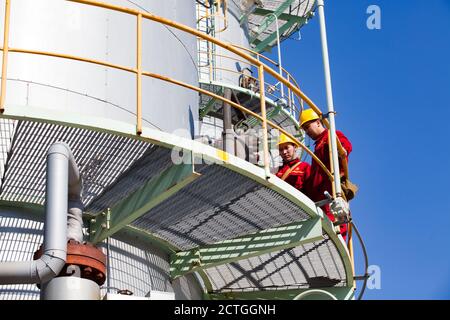 chemical industry plant - workers in work clothes in a refinery with ...