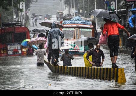 People walk through a waterlogged street during heavy rain in Mumbai ...