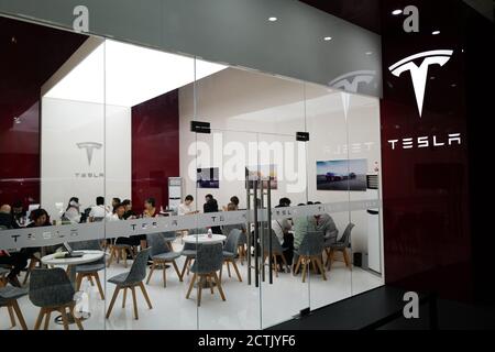Visitors flock to the booth of Tesla, an American electric vehicle and ...