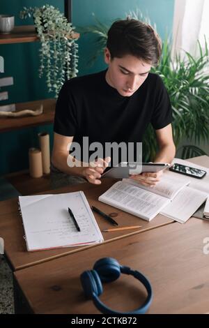 Young student doing homework with digital tablet in the living room ...