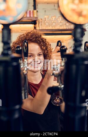 Female bartender tapping beer in bar, pouring from tap into the glass ...