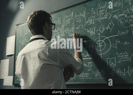 Young mathematician solving problems and writing formulas on the ...