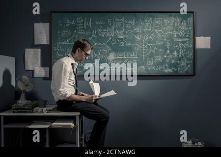 Brilliant mathematician working in his office, he is reviewing his ...