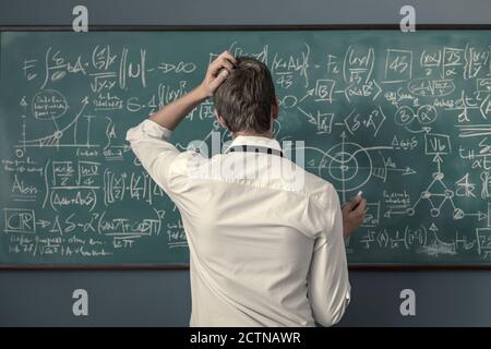 Young mathematician solving problems and writing formulas on the ...